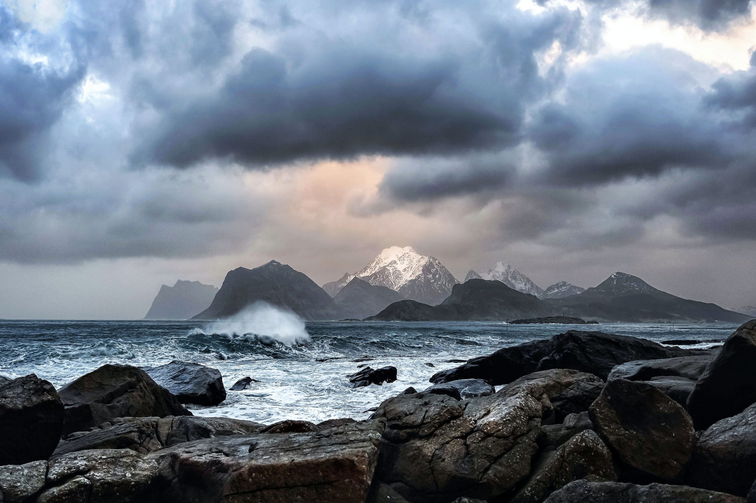 Waves crashing on rocks near mountains in Myrland, Norway - Beach ...
